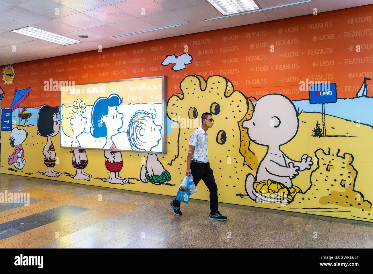 A subway passenger is seen walking through the mural Snoopy and Friends ...