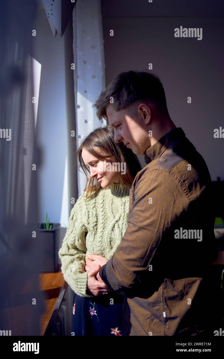 a beautiful young couple kissing near the window Stock Photo - Alamy