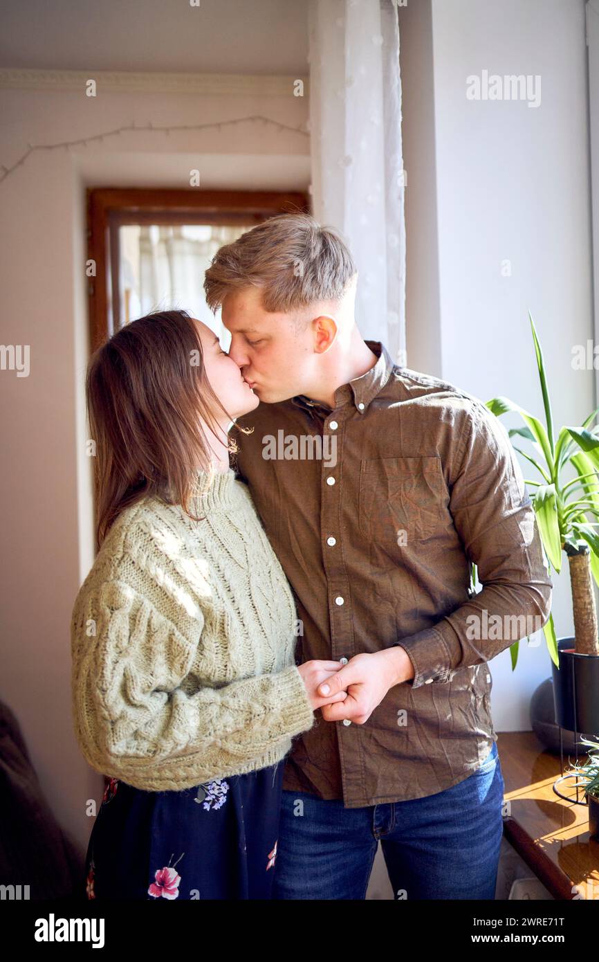 a beautiful young couple kissing near the window Stock Photo - Alamy