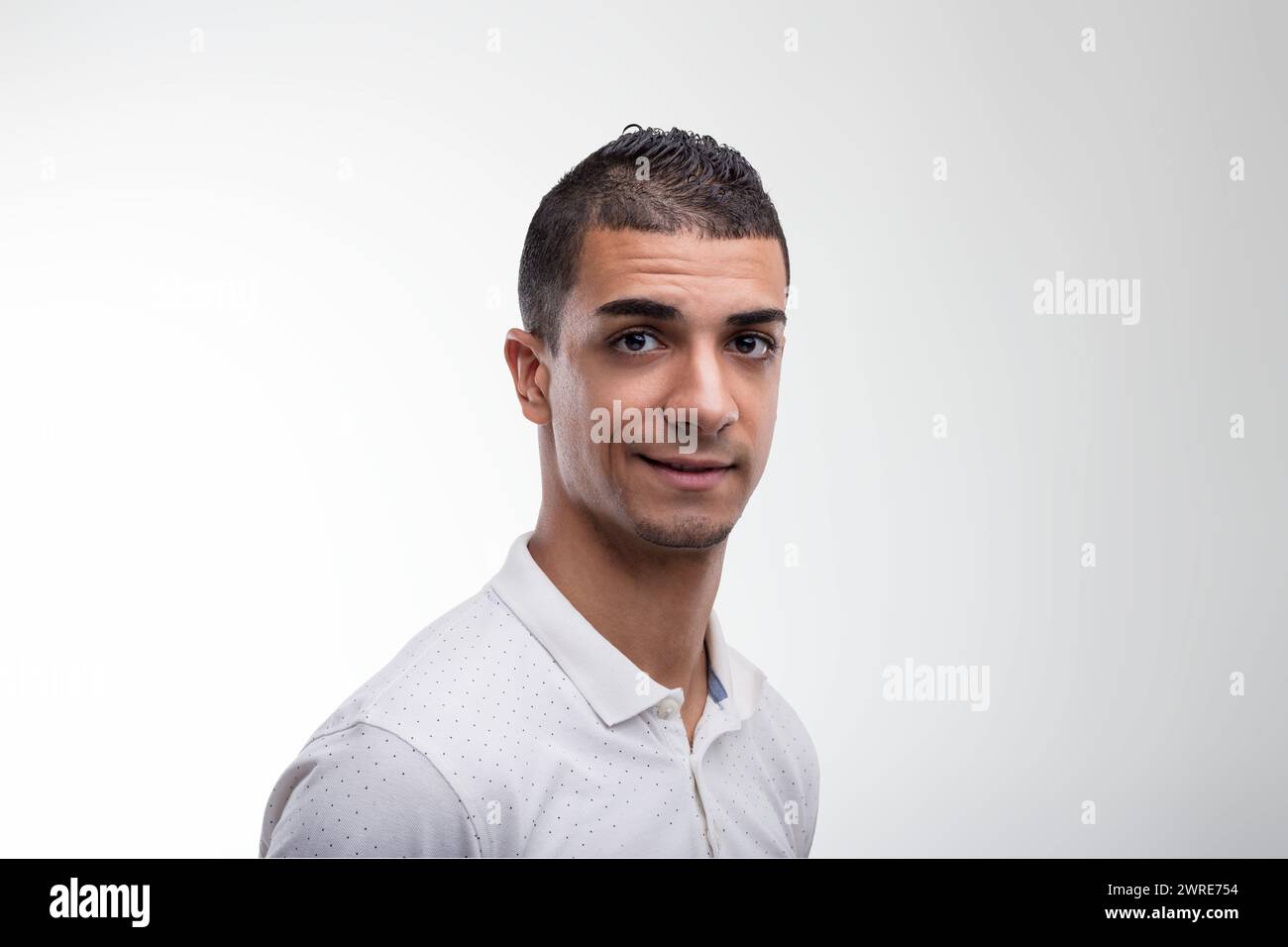 Confident young man in casual attire presents a calm demeanor against a ...