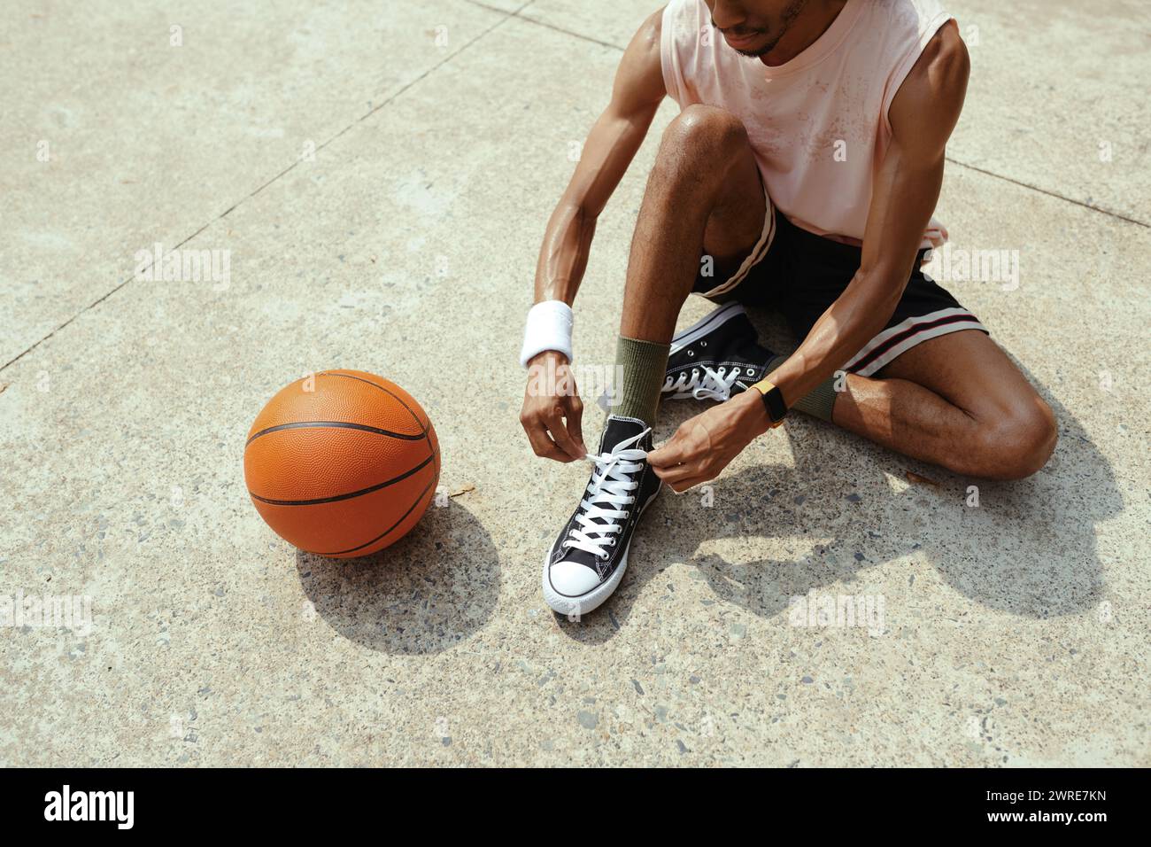 Sweaty street ball player tying shoe laces after game Stock Photo - Alamy