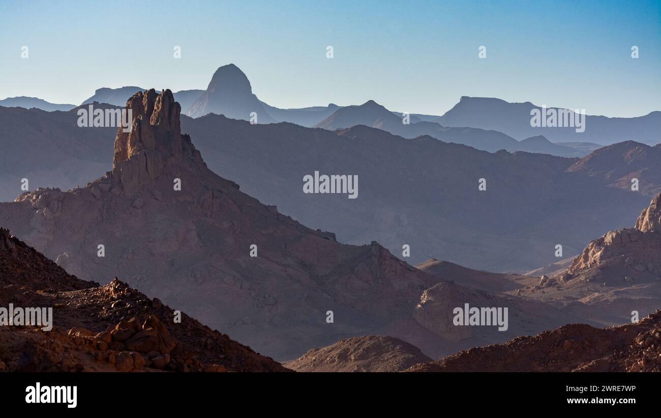 Hoggar landscape in the Sahara desert, Algeria. Steep peaks rise up in ...