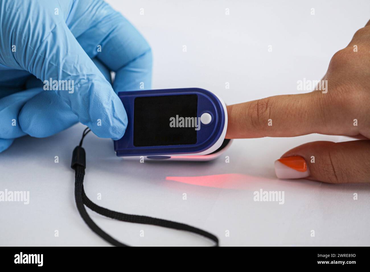 Doctor examining patient with fingertip pulse oximeter in bed, closeup ...