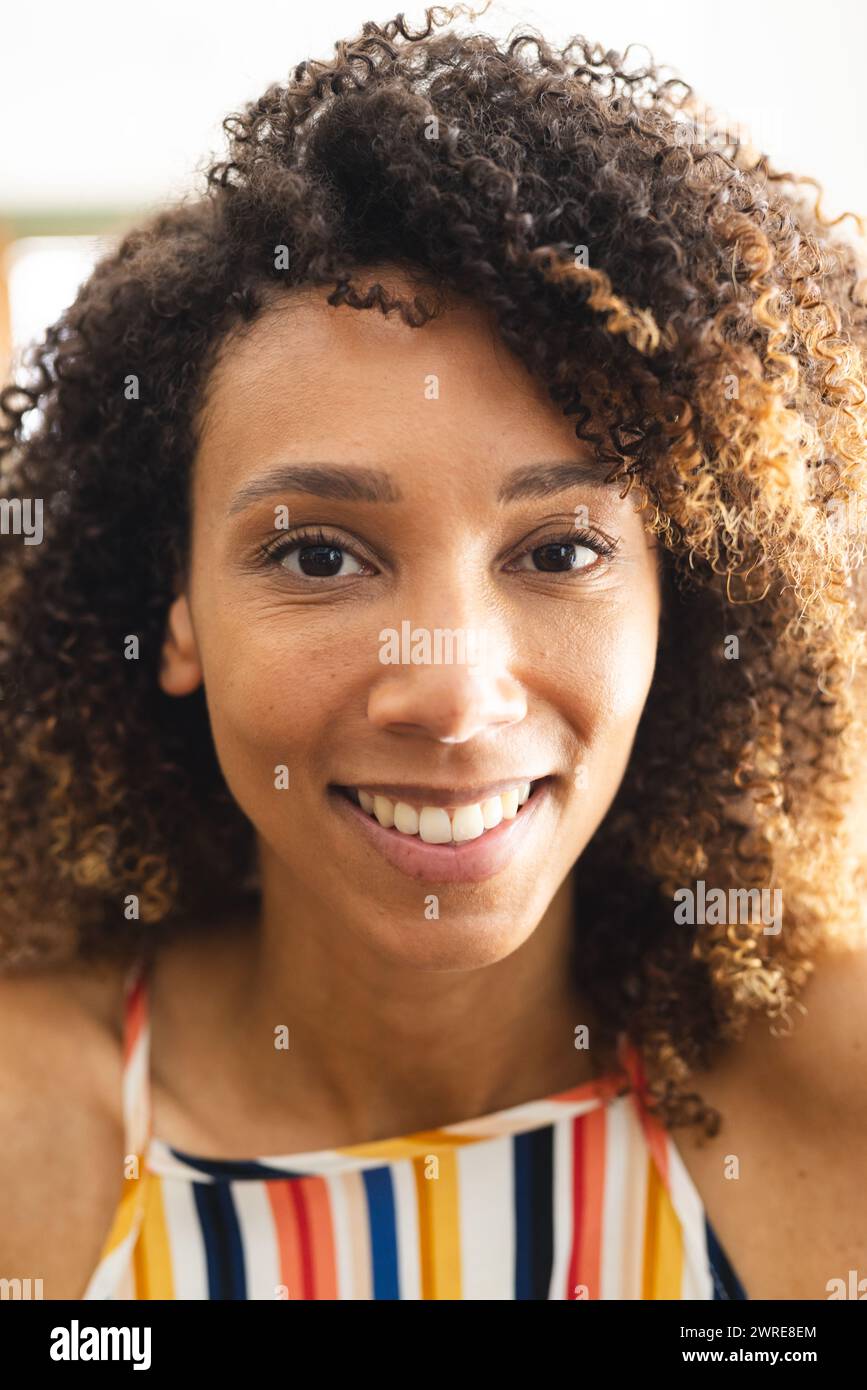 Biracial woman with curly hair smiles warmly, her eyes gleaming with ...