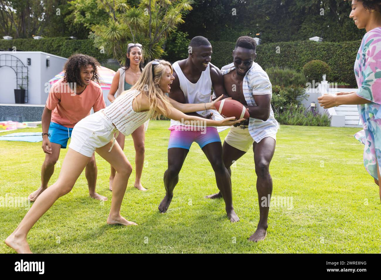 Diverse group of friends playing football in a sunny backyard, laughter ...