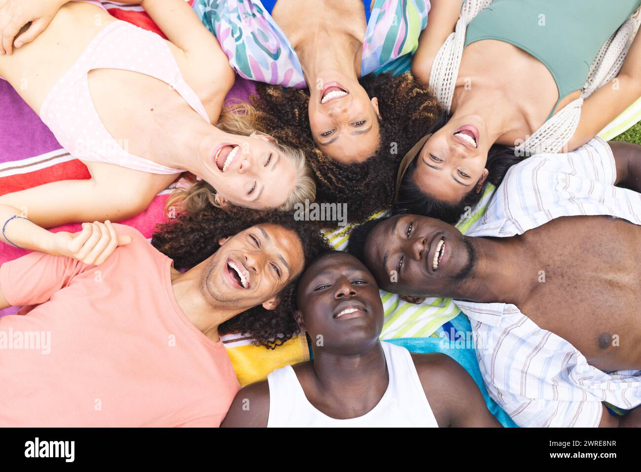 Diverse group of friends lying down close together, smiling at the ...