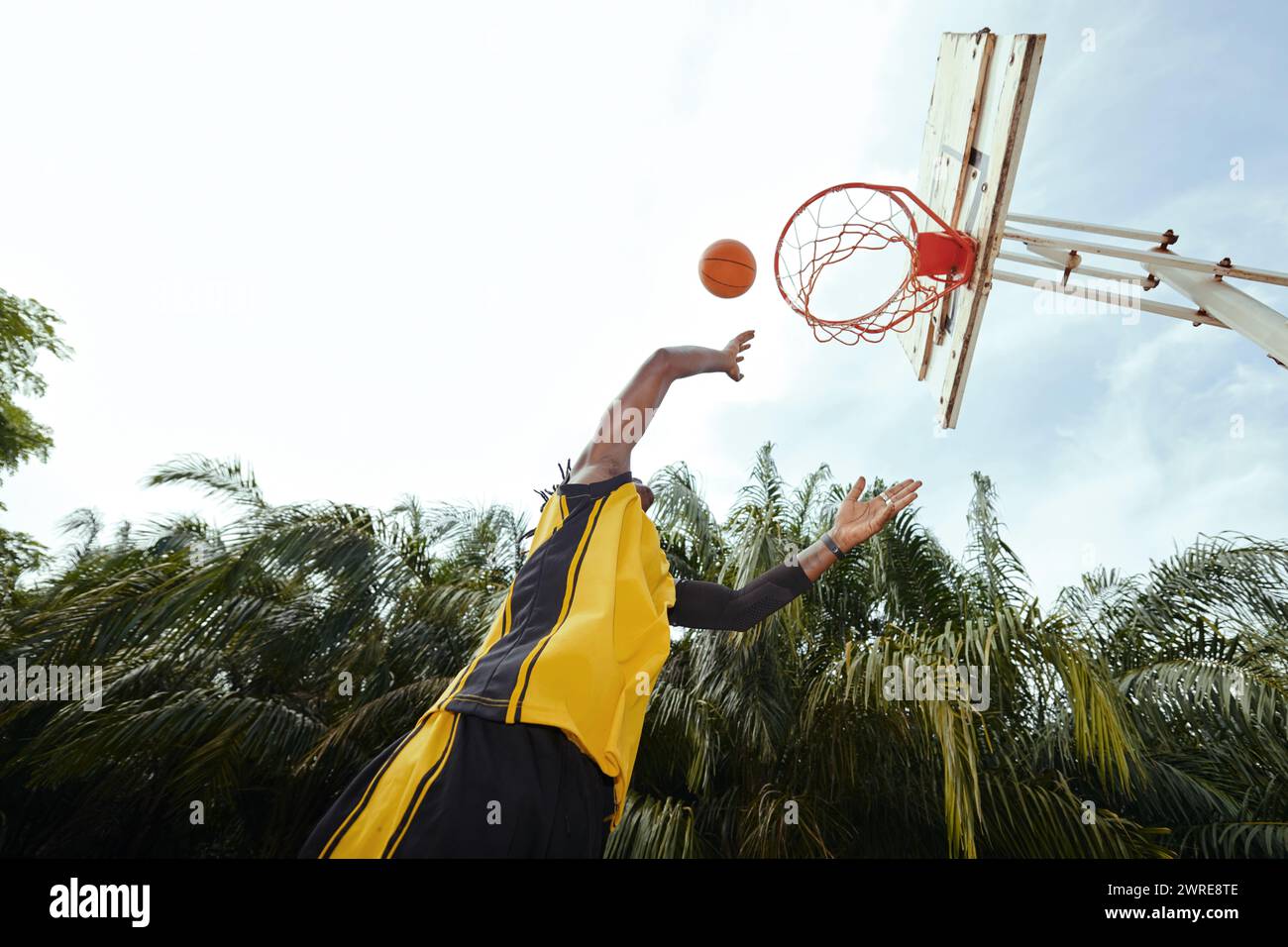 Player throwing ball in basket when playing outdoors, view from below ...