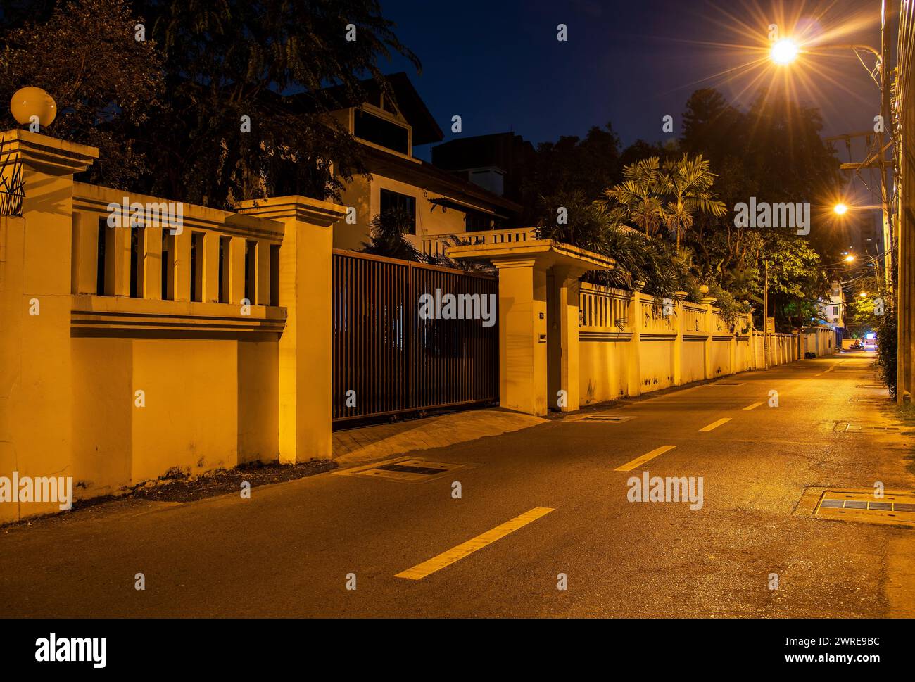 A street at night with a white house and a gate Stock Photo - Alamy