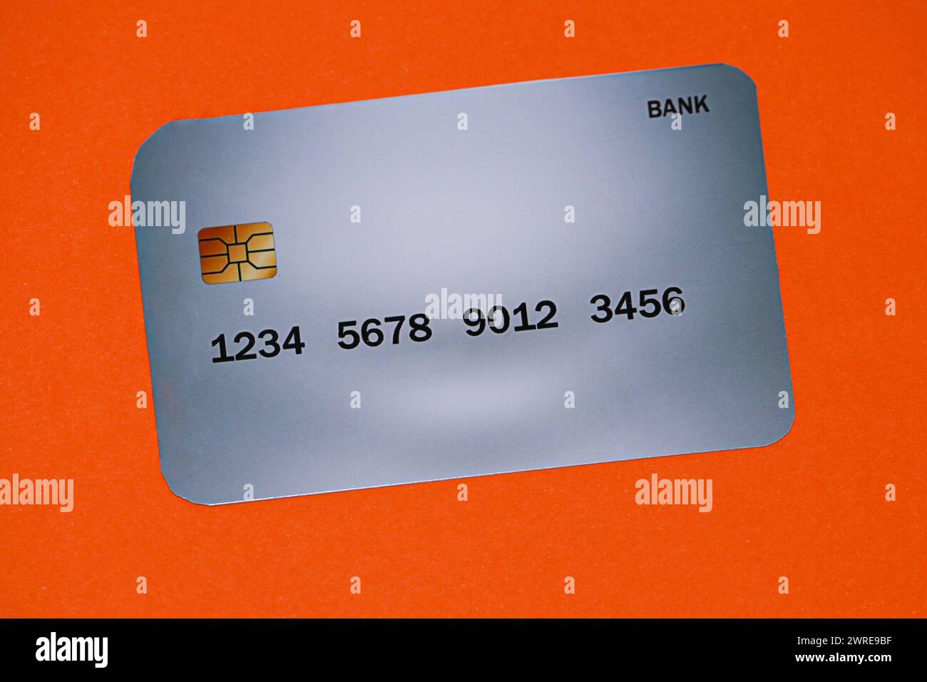 Picture on an orange background that has a gray bank card on it, a very ...