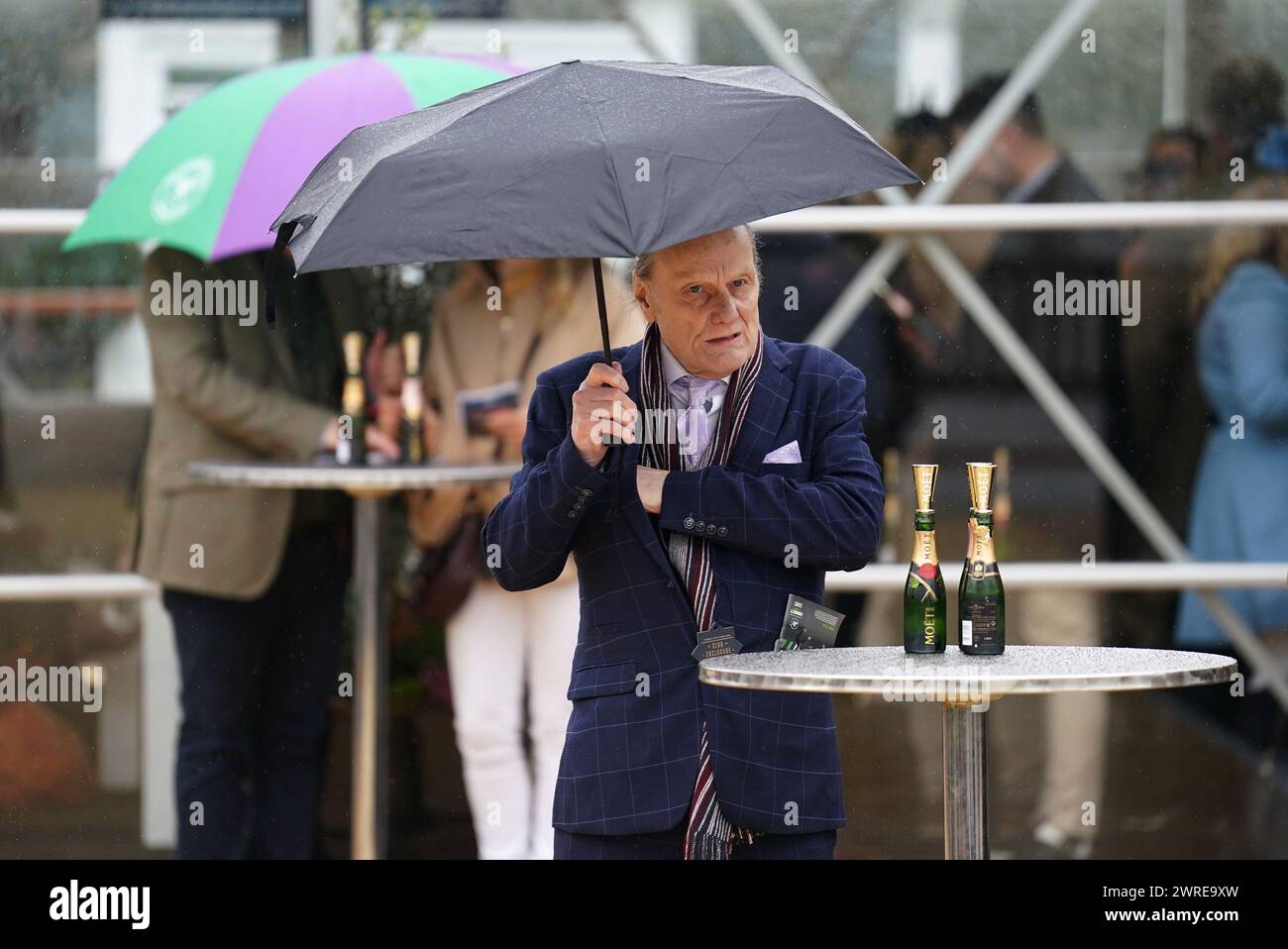 A racegoer shelters from the rain on day one of the 2024 Cheltenham ...