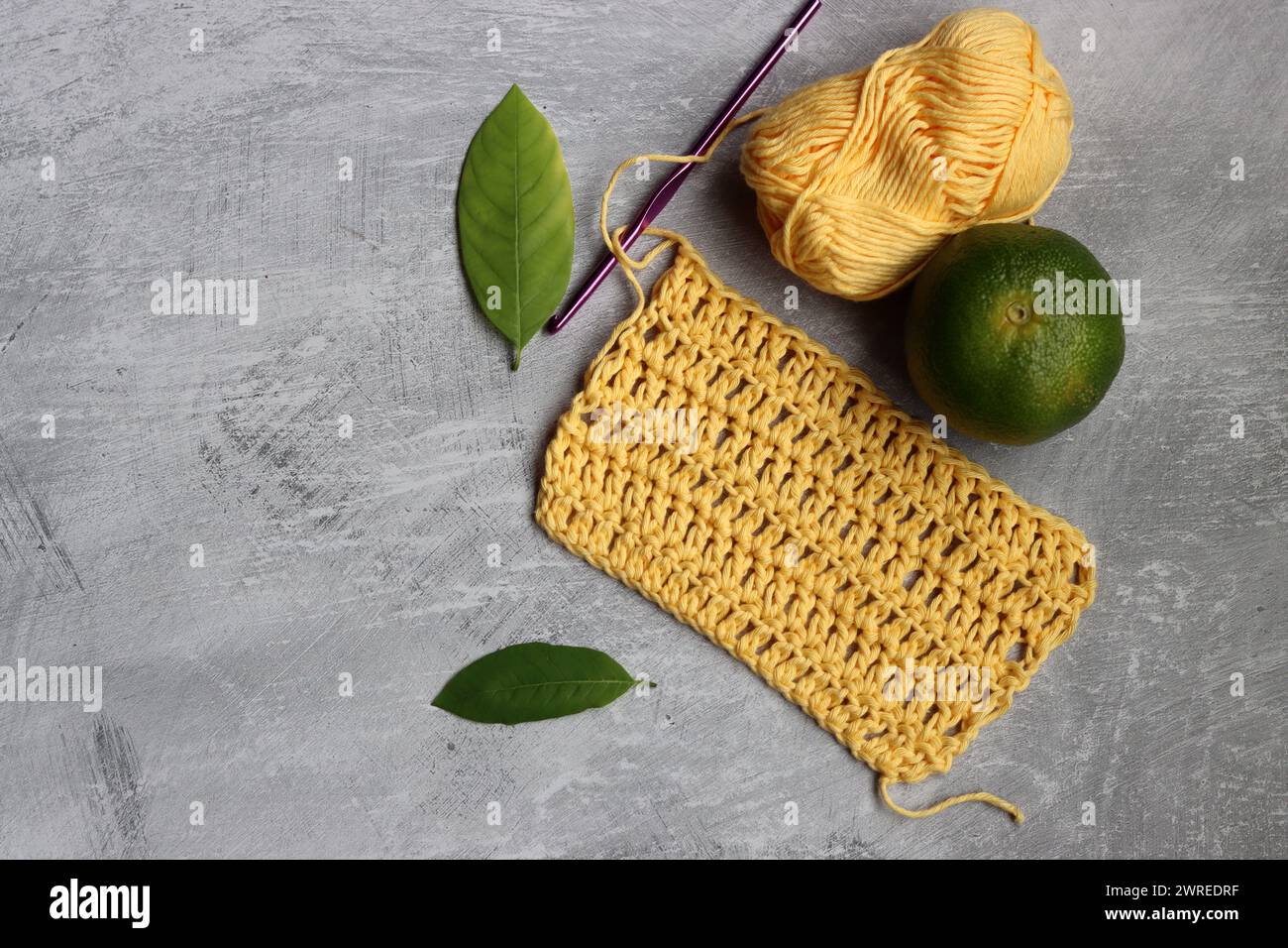Yellow crochet DIY project. Organic cotton yarn on grey background with ...