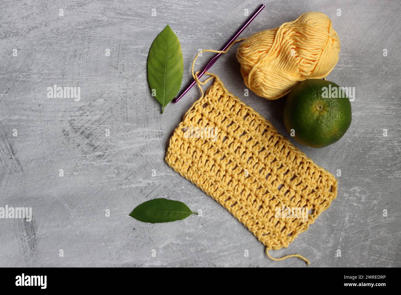 Yellow crochet DIY project. Organic cotton yarn on grey background with ...