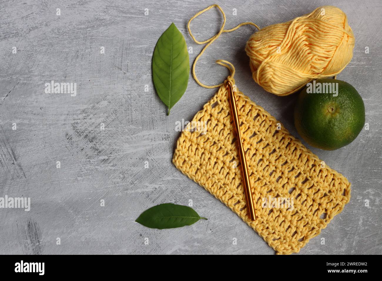 Yellow crochet DIY project. Organic cotton yarn on grey background with ...