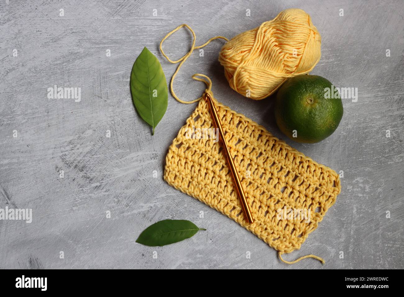 Yellow crochet DIY project. Organic cotton yarn on grey background with ...