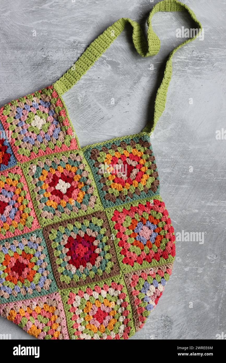 Handmade crocheted bag on grey textured background, top view. Close up ...