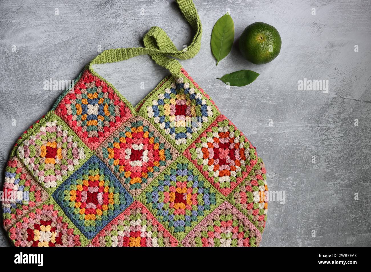 Handmade crocheted bag on grey textured background, top view. Close up ...