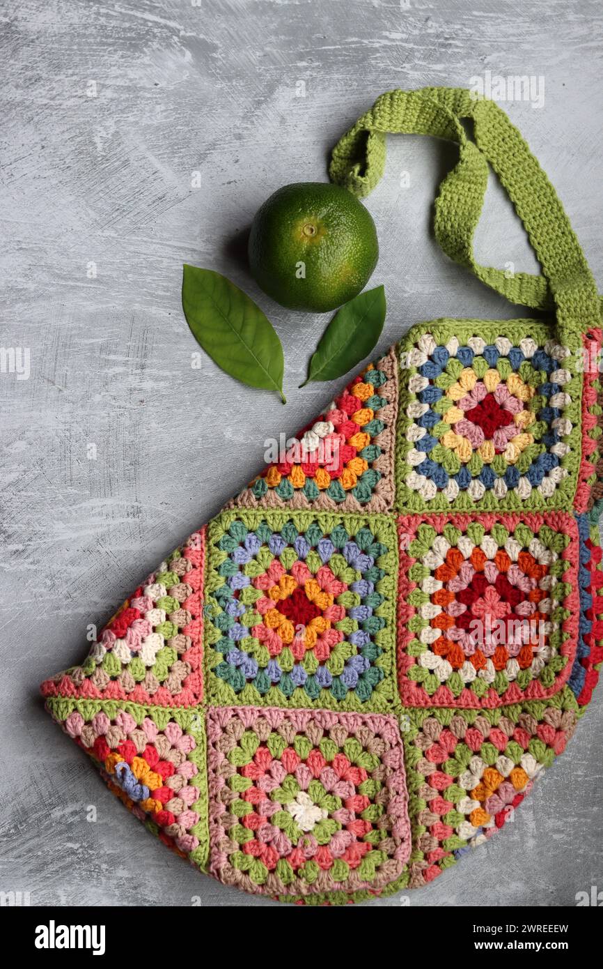 Handmade crocheted bag on grey textured background, top view. Close up ...