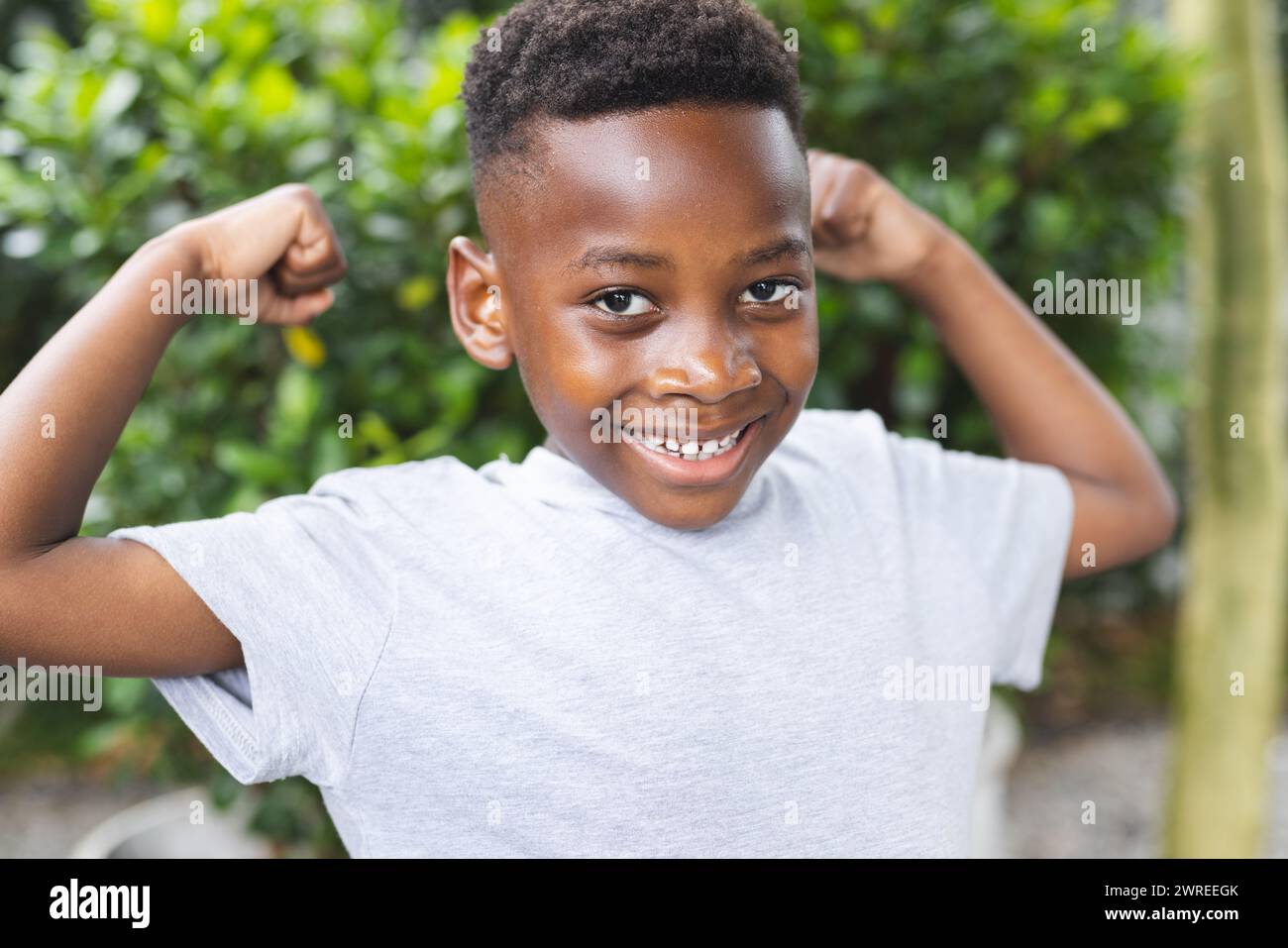 African American boy flexes his muscles with a confident smile in a ...