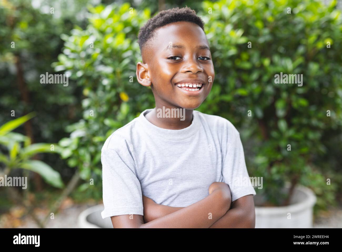 African American boy smiles with arms crossed, wearing a gray shirt in ...