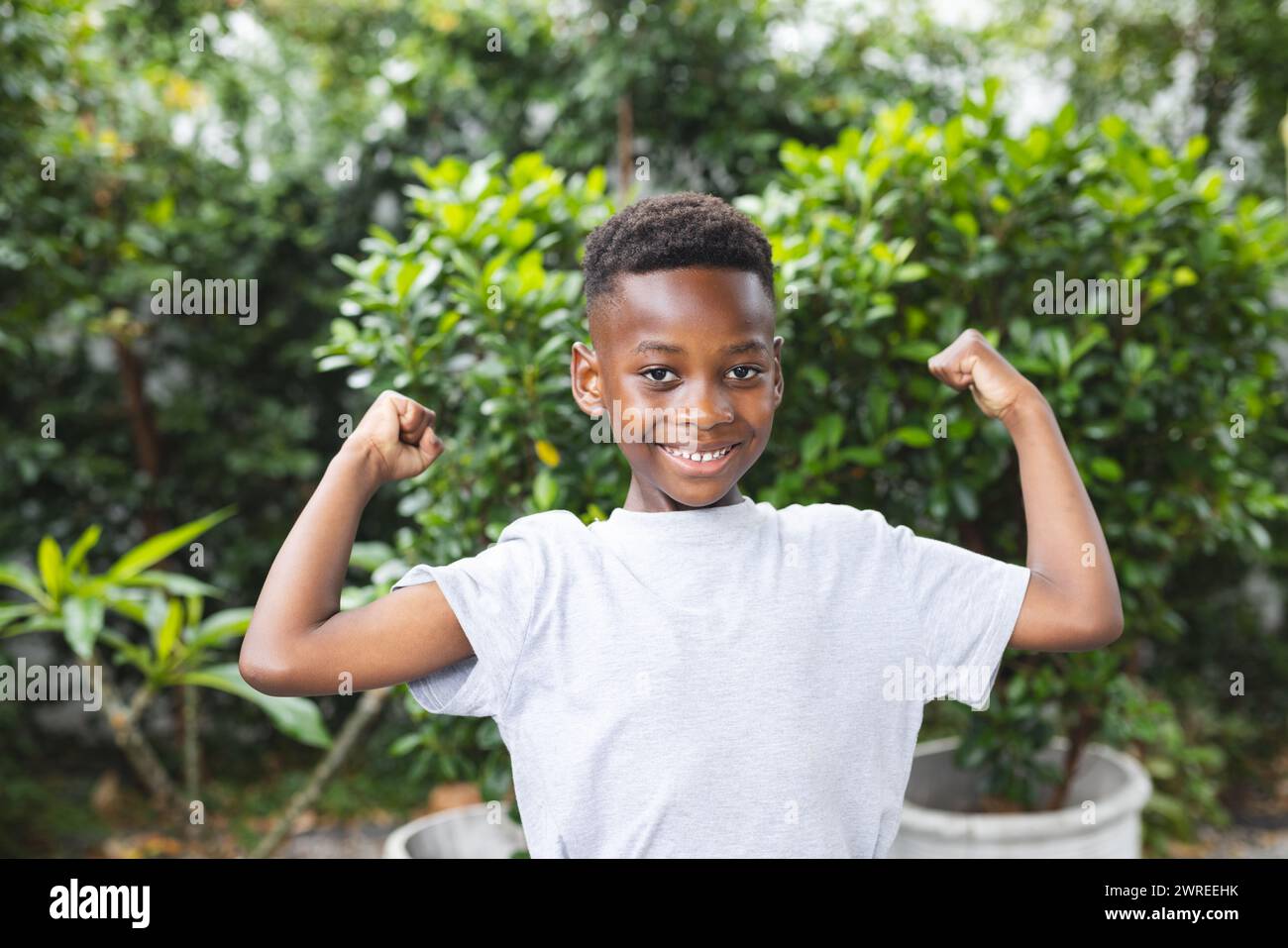 African American boy flexes his muscles with a confident smile in a ...