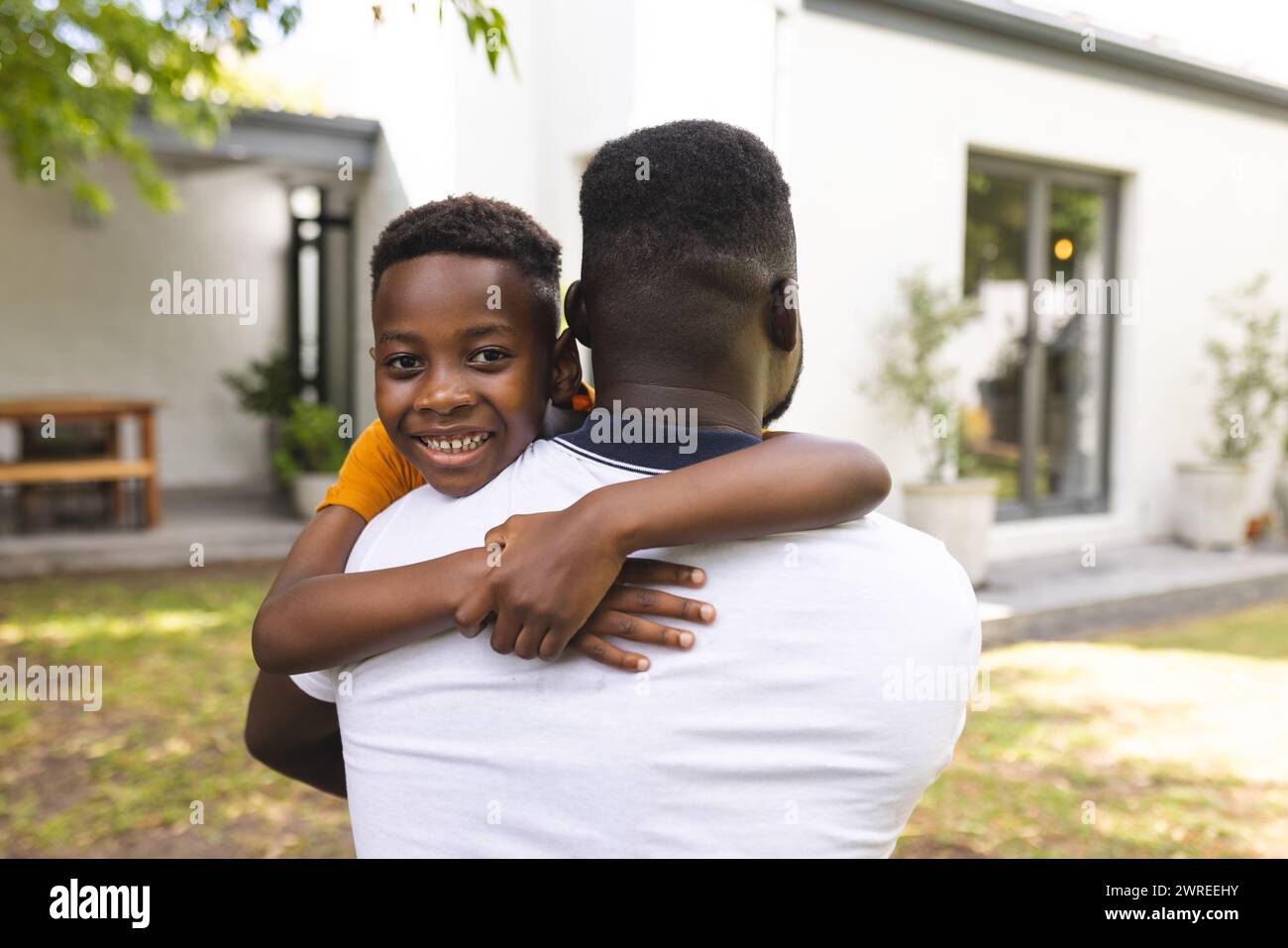 African American father embraces his son in a warm hug outdoors in the ...