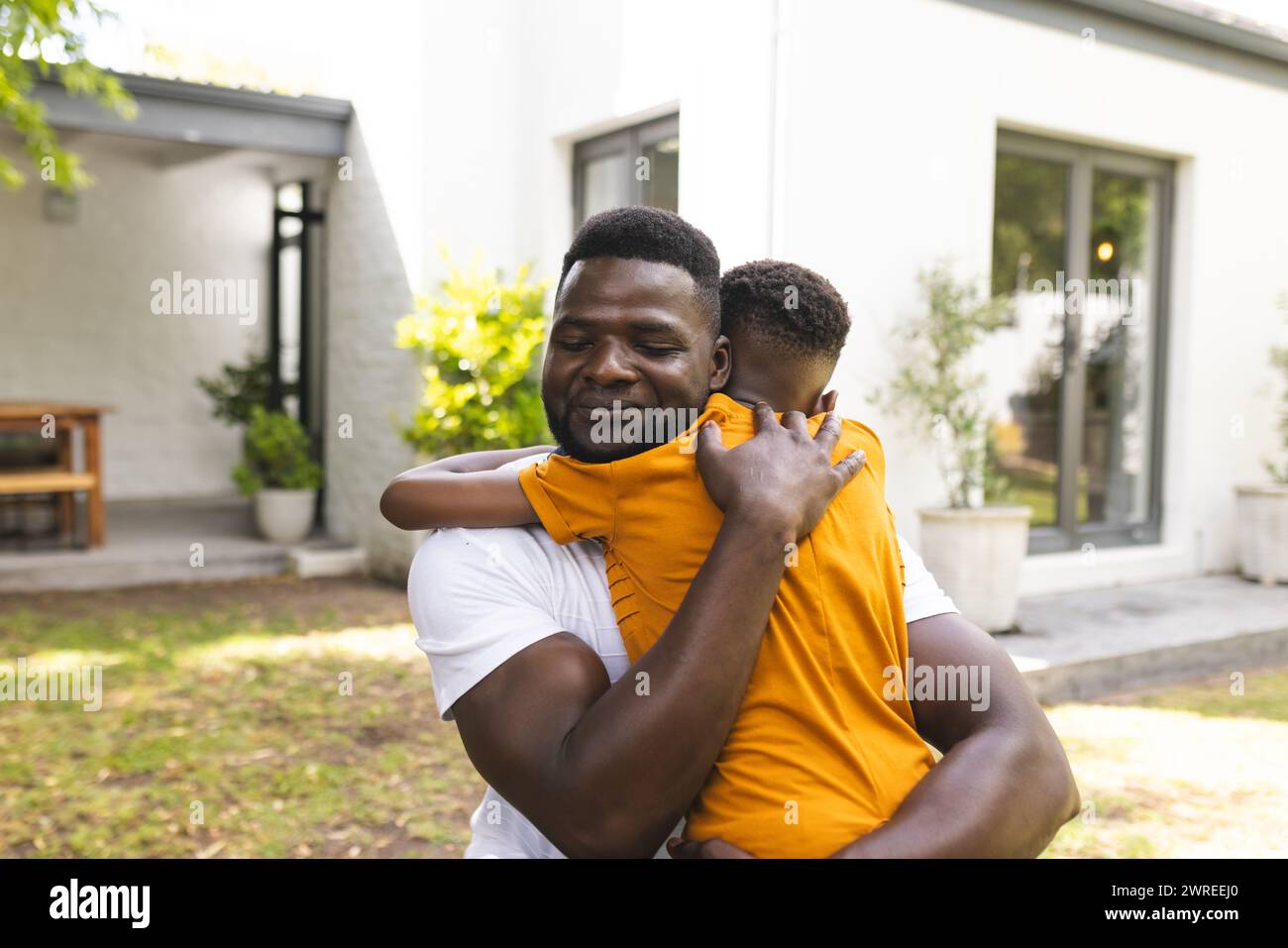 African American father embraces his son in a warm hug outdoors in the ...