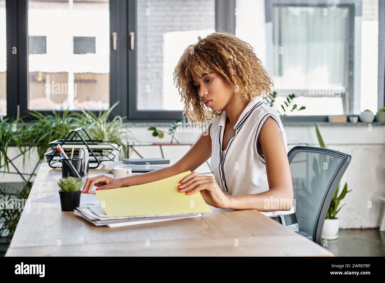 Focused african american businesswoman with curly hair reviewing files ...