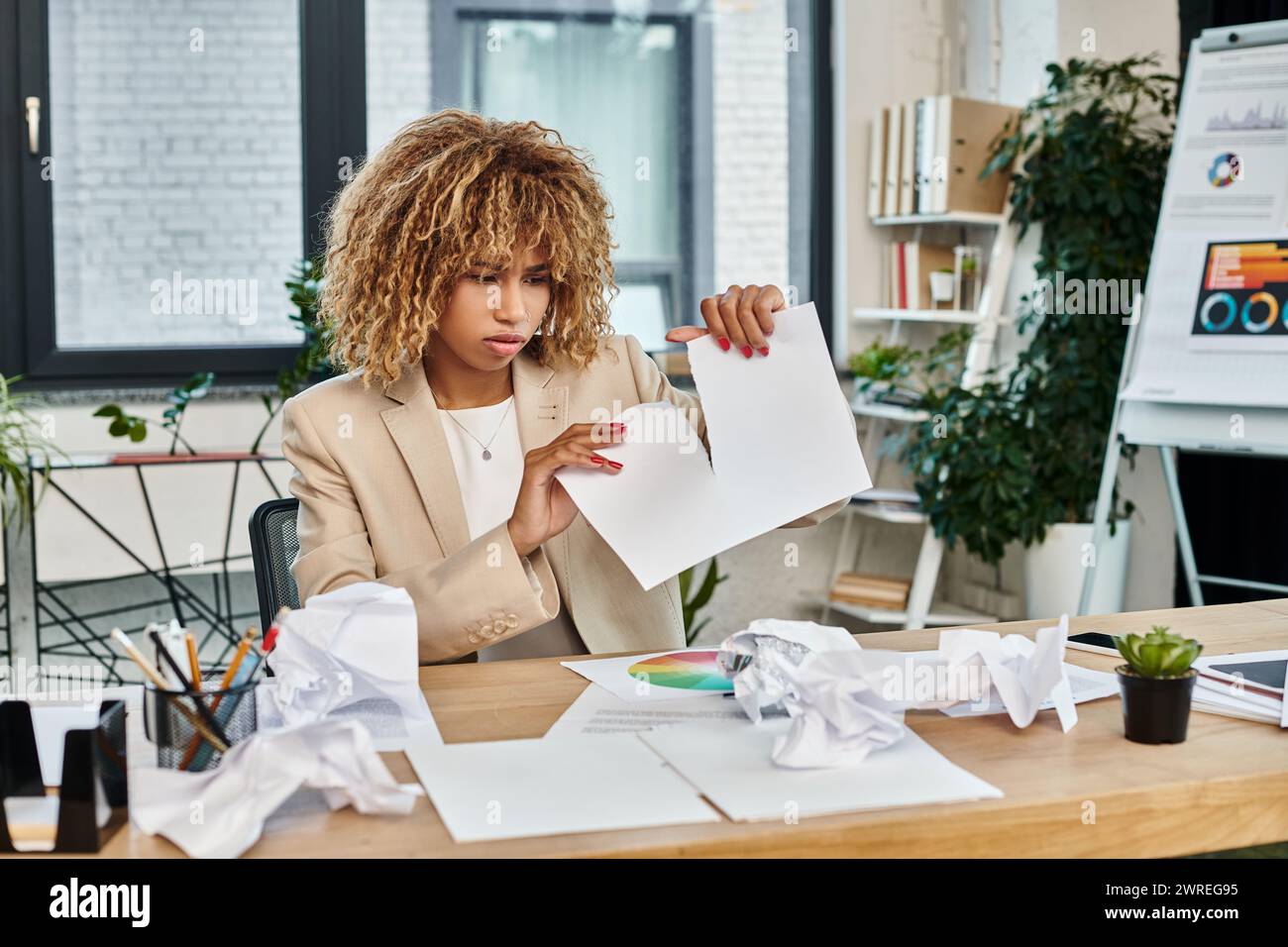 upset and curly african american businesswoman in formal wear ripping ...