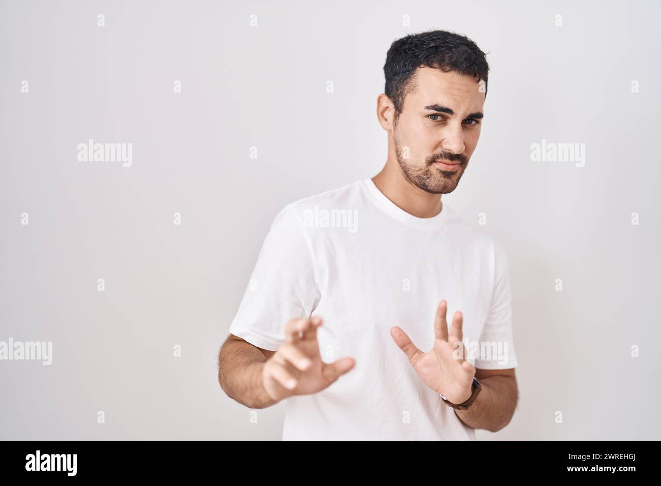 Handsome hispanic man standing over white background disgusted ...