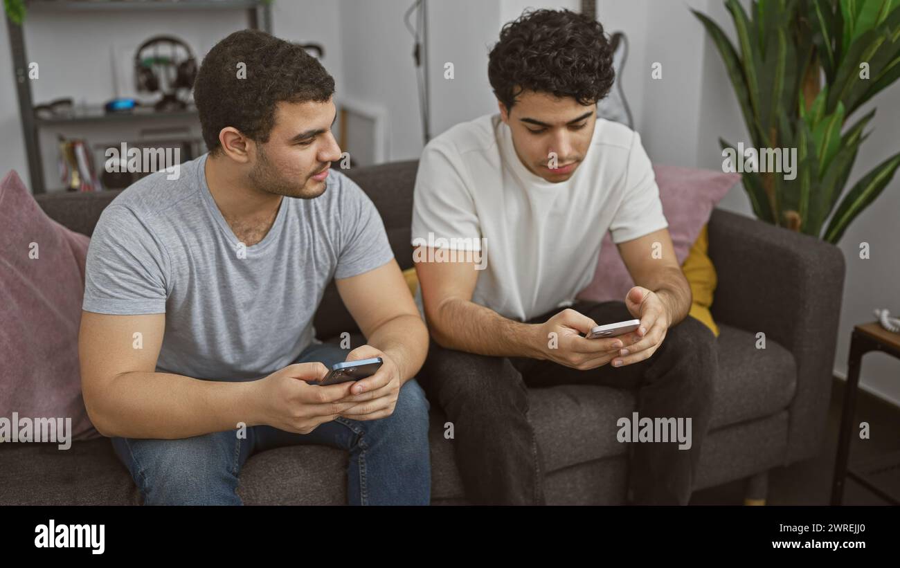 Two men engaged with smartphones in a modern living room Stock Photo ...