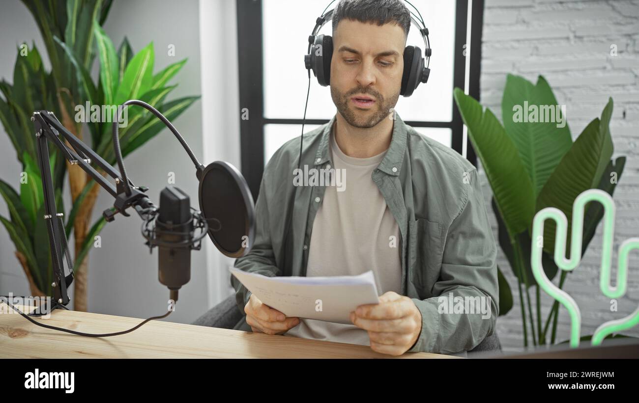 Handsome bearded man in headphones reading script indoors at a modern ...