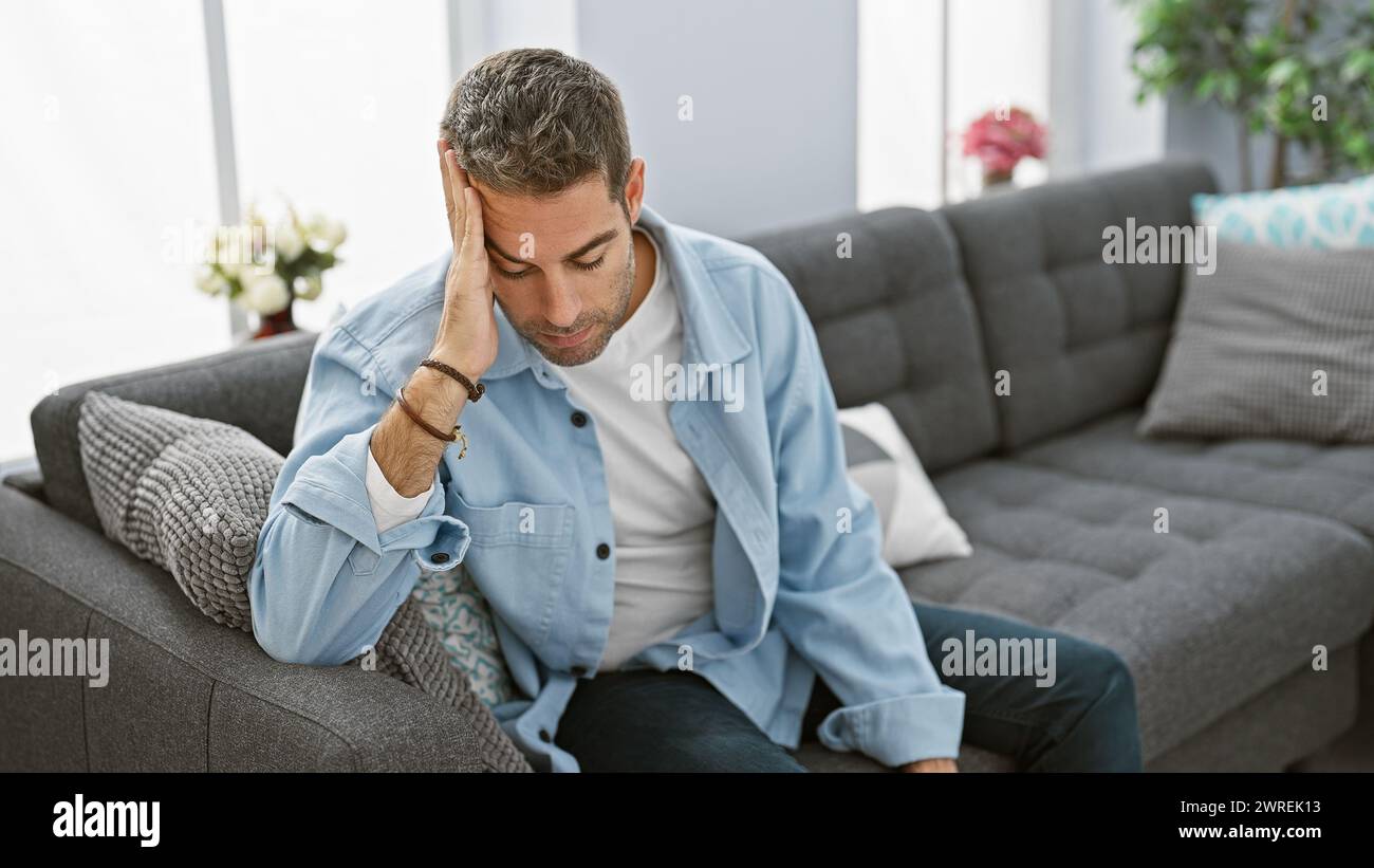 Stressed man sitting thoughtfully in a modern living room displaying ...