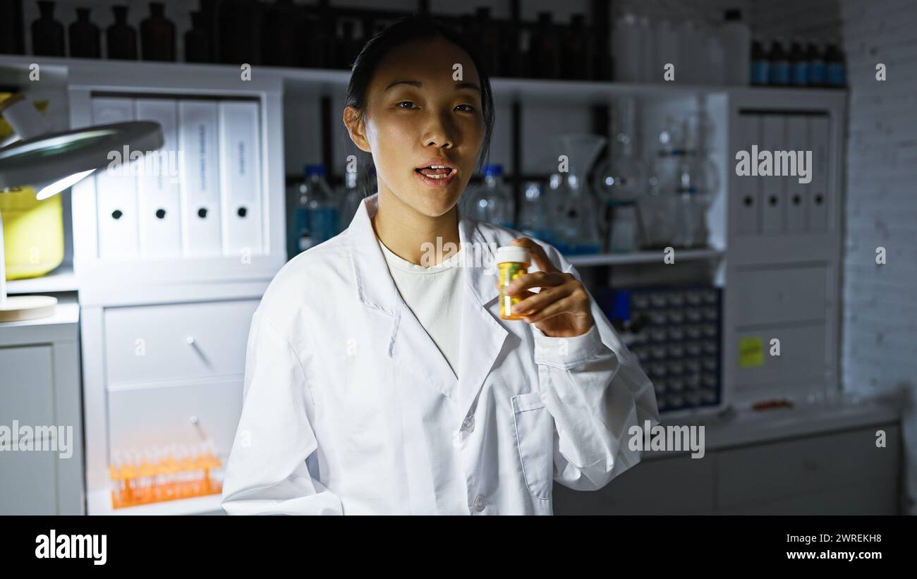 A young asian woman in a lab coat examines medication in a pharmacy ...