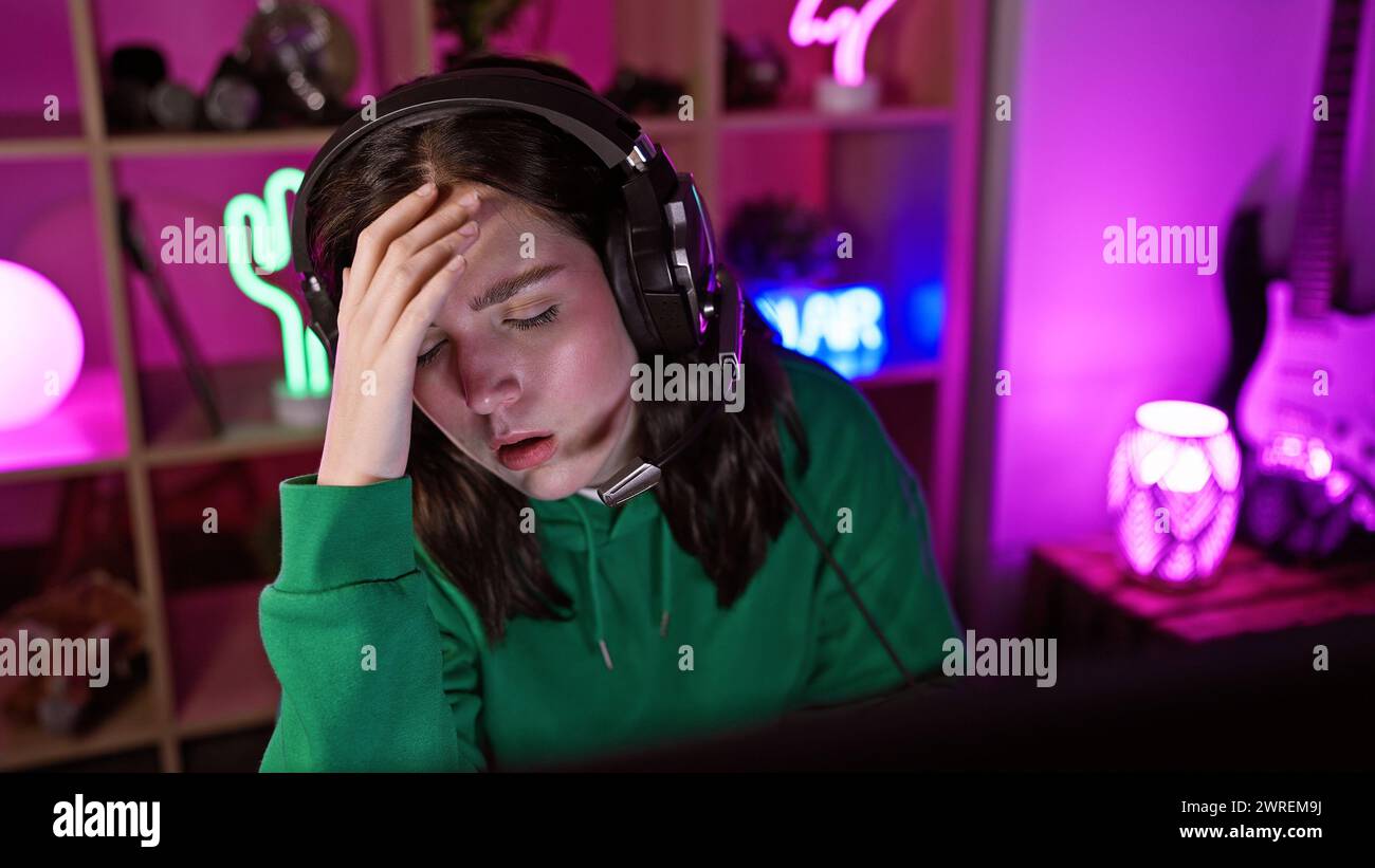 A stressed young woman gamer in headphones experiencing defeat in a ...