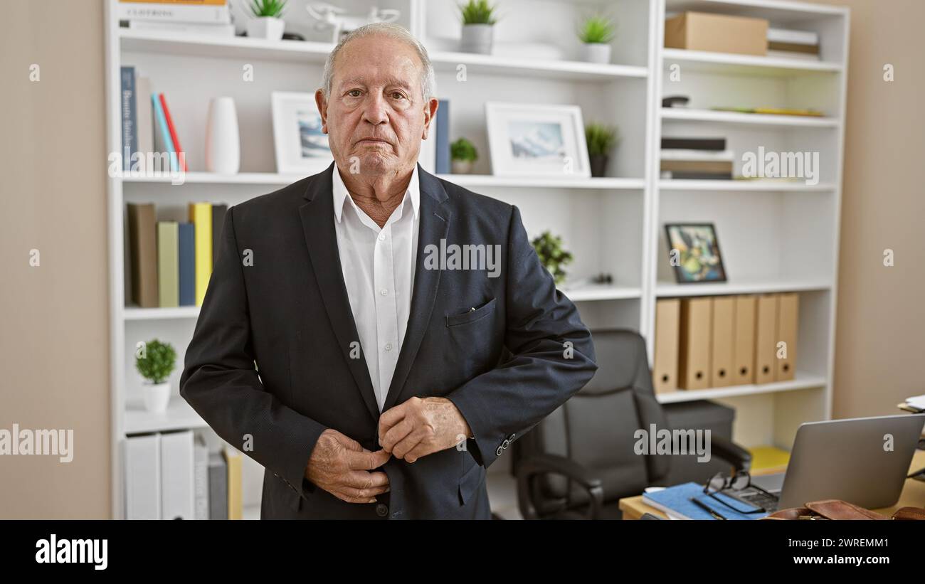 Serious-faced, senior businessman standing confidently in an office ...