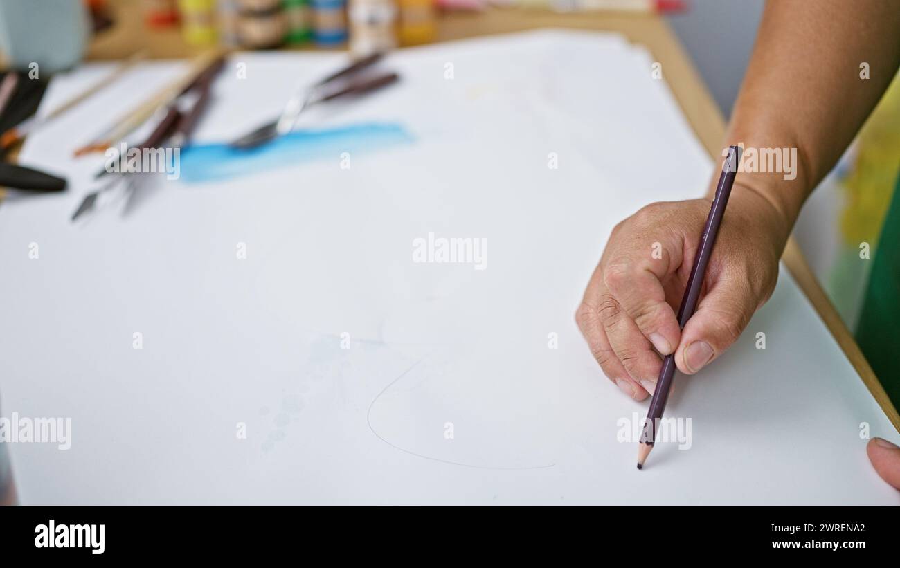 Passionate young latin artist immersed in drawing on his notebook ...