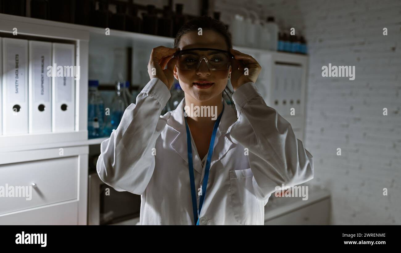 A young hispanic woman scientist in a lab wearing safety goggles and a ...