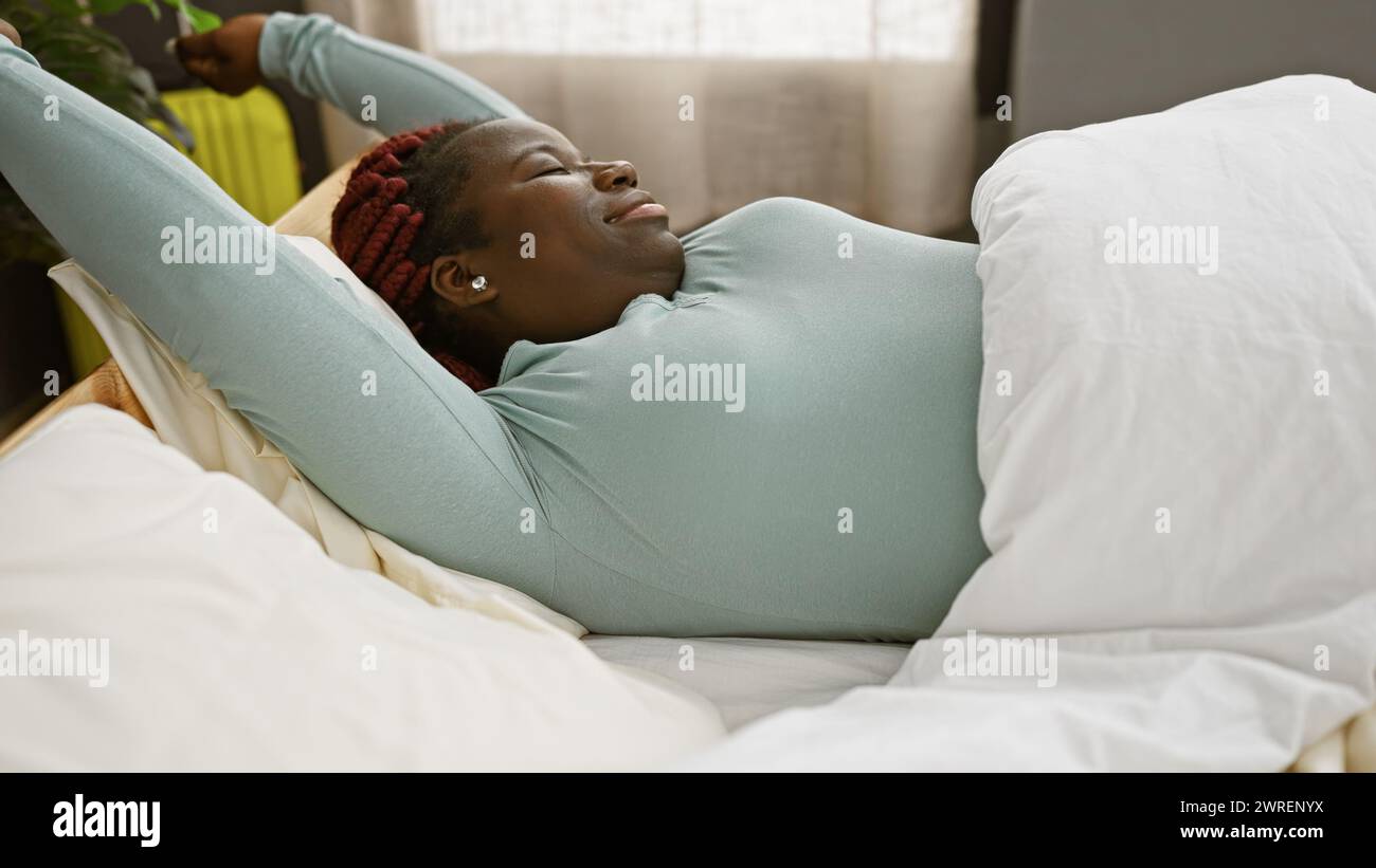 A relaxed african american woman with braids stretching arms while ...