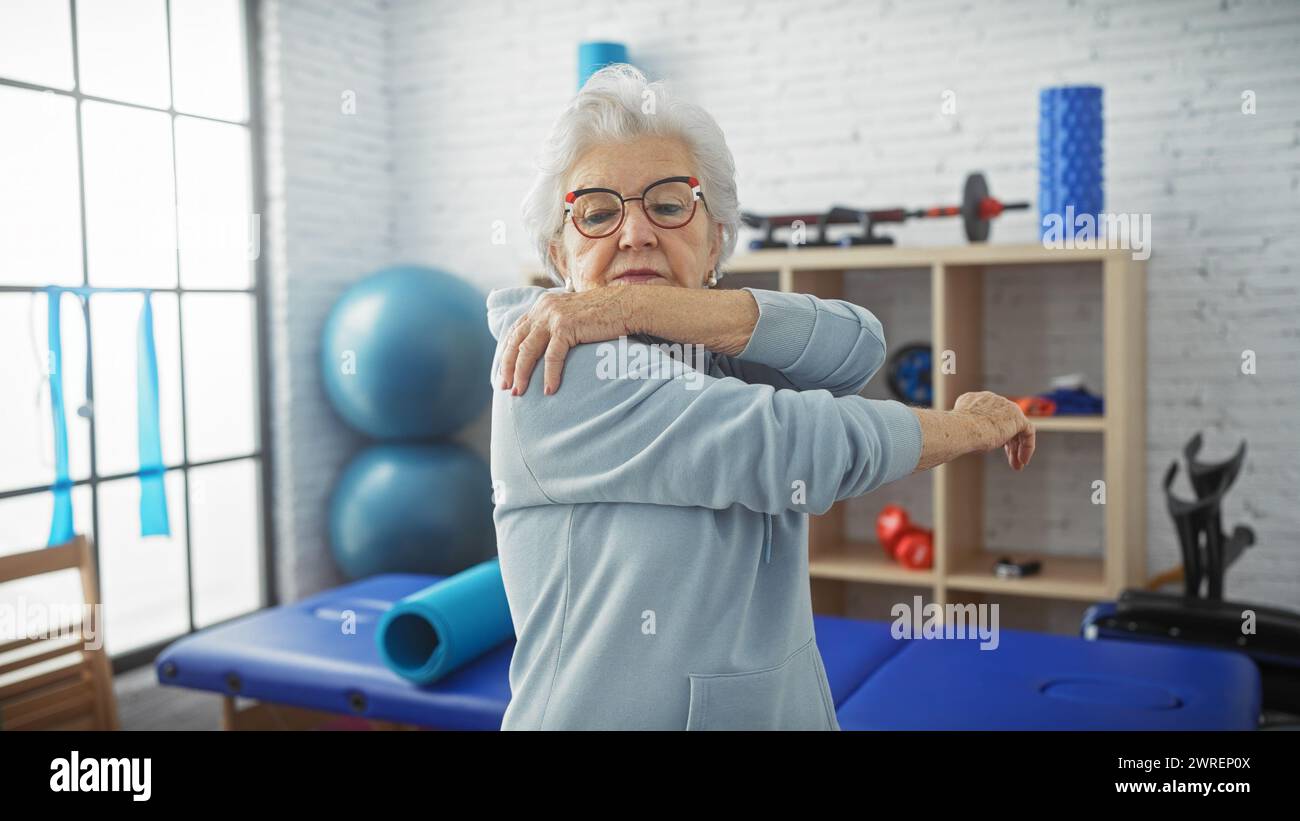 Senior woman stretching in a physiotherapy rehab clinic room with ...