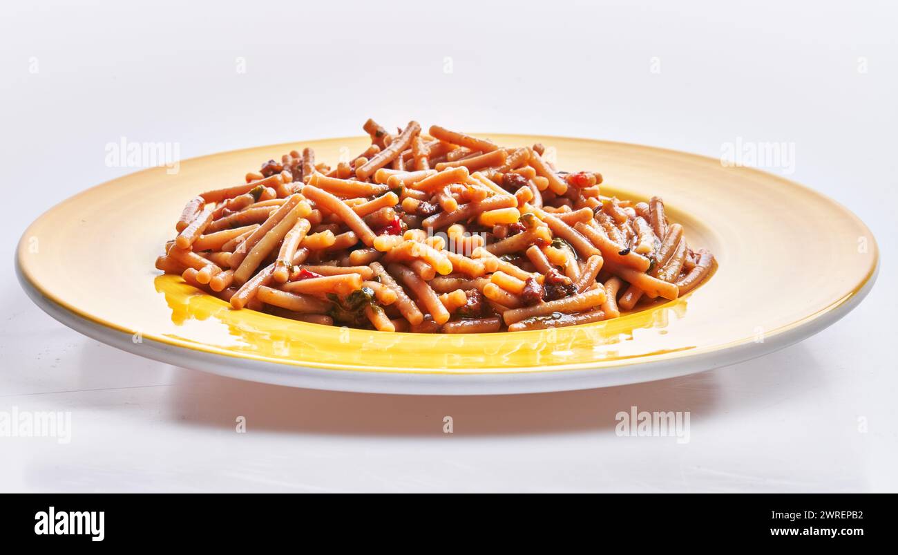 A sumptuous plate of pasta covered in tomato sauce served on a yellow ...