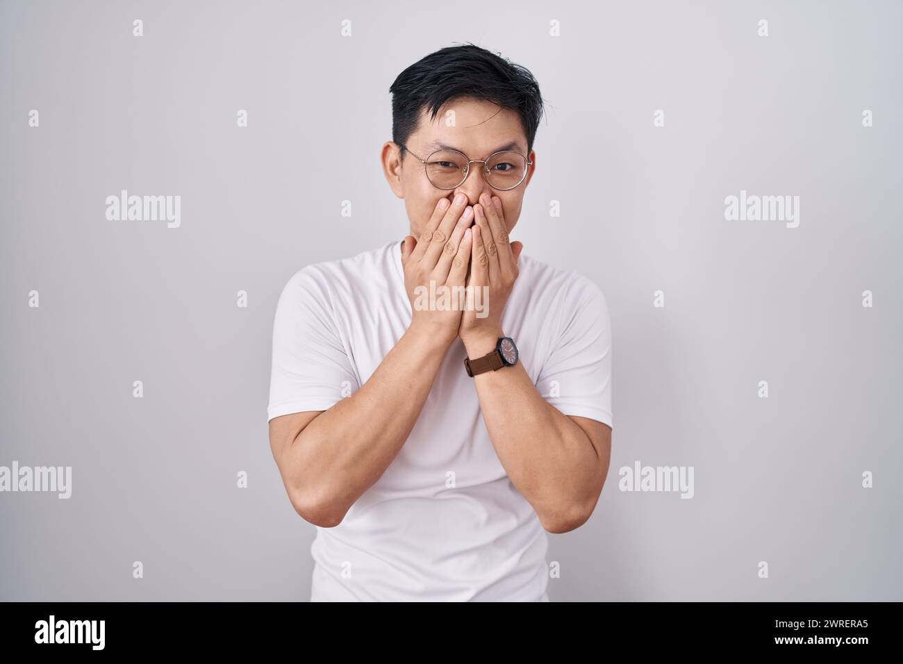 Young asian man standing over white background laughing and embarrassed ...