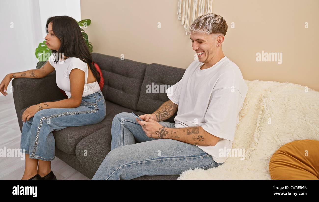 A man and woman sit apart on a sofa in a modern living room, showcasing ...