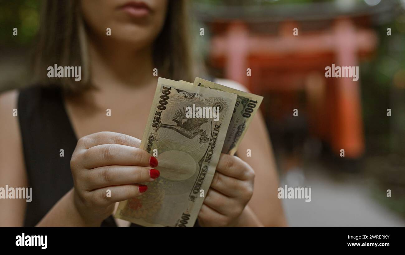 Caucasian young woman counting banknotes of japanese yen amidst scarlet ...