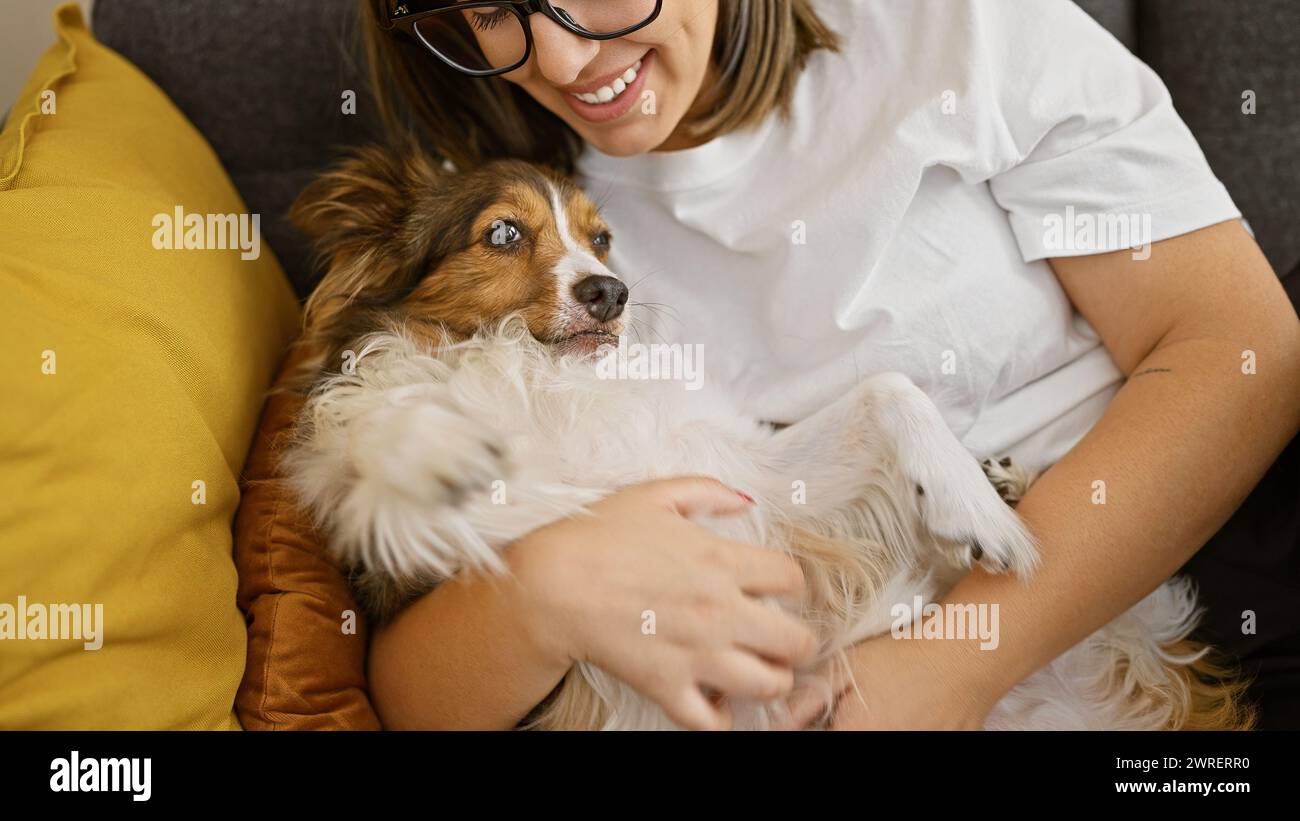 Hispanic woman cuddling with dog in a cozy living room setting ...