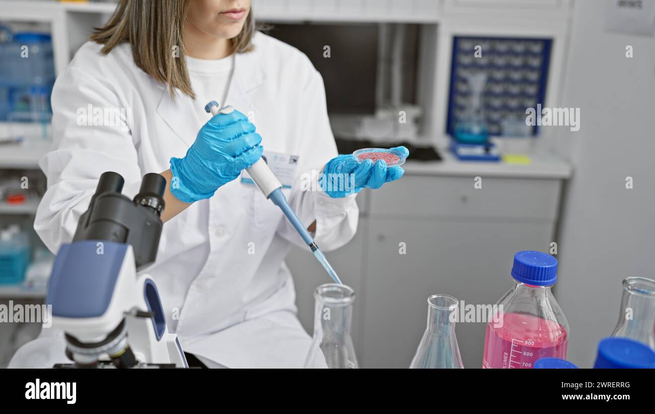 Focused woman in lab conducts experiment with pipette and test tube, in ...