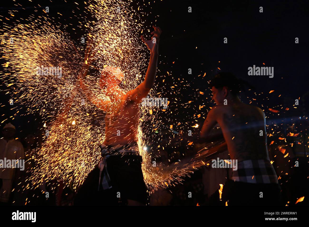 A Hindu devout hits another with burning coconut leaves, sending sparks ...