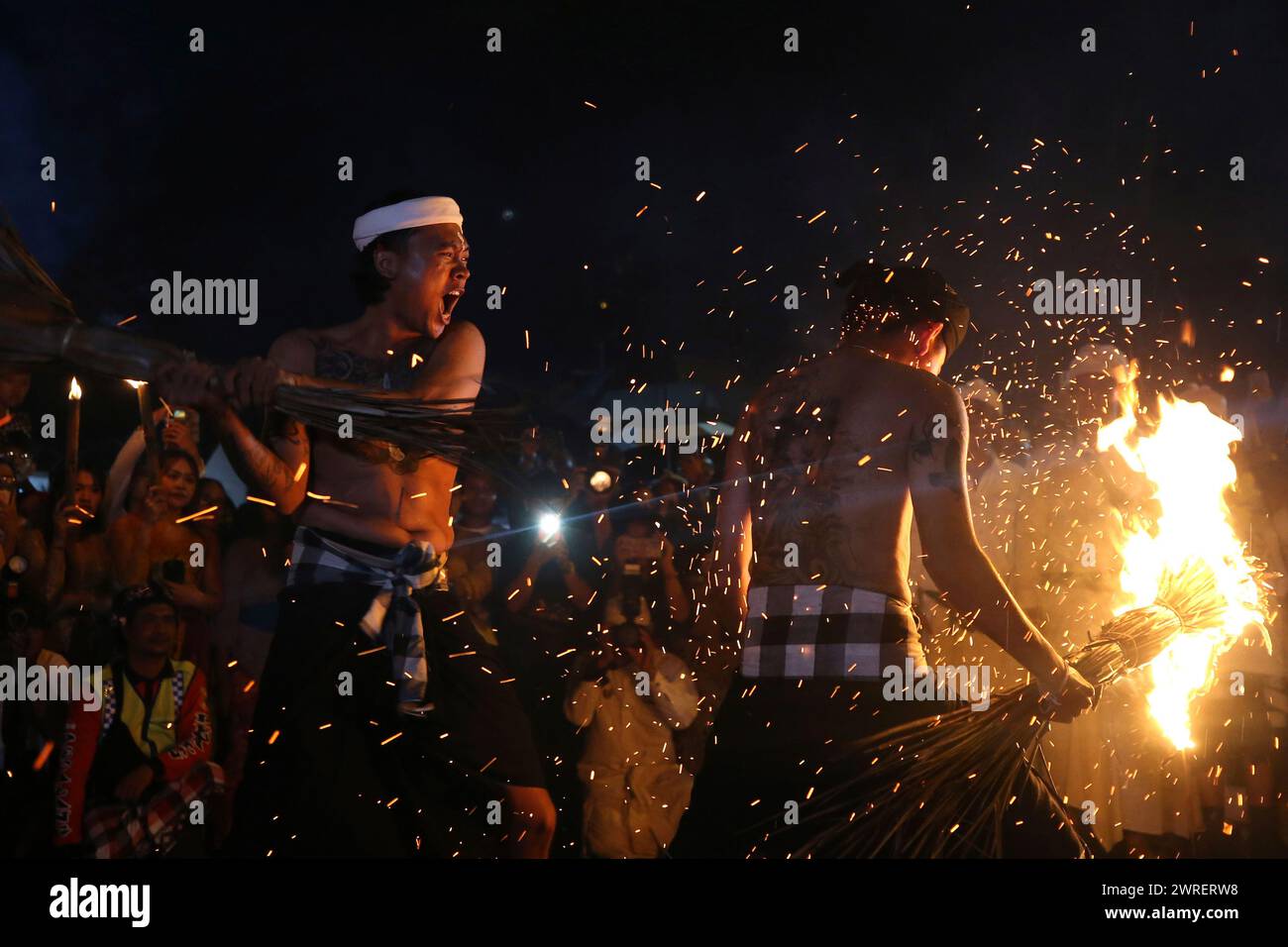 A Hindu devout hits another with burning coconut leaves, sending sparks ...