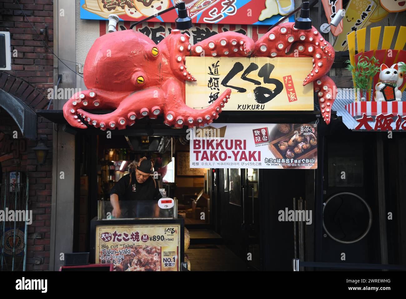 Japanese man preparing takoyaki, a ball-shaped Japanese snack made of a ...