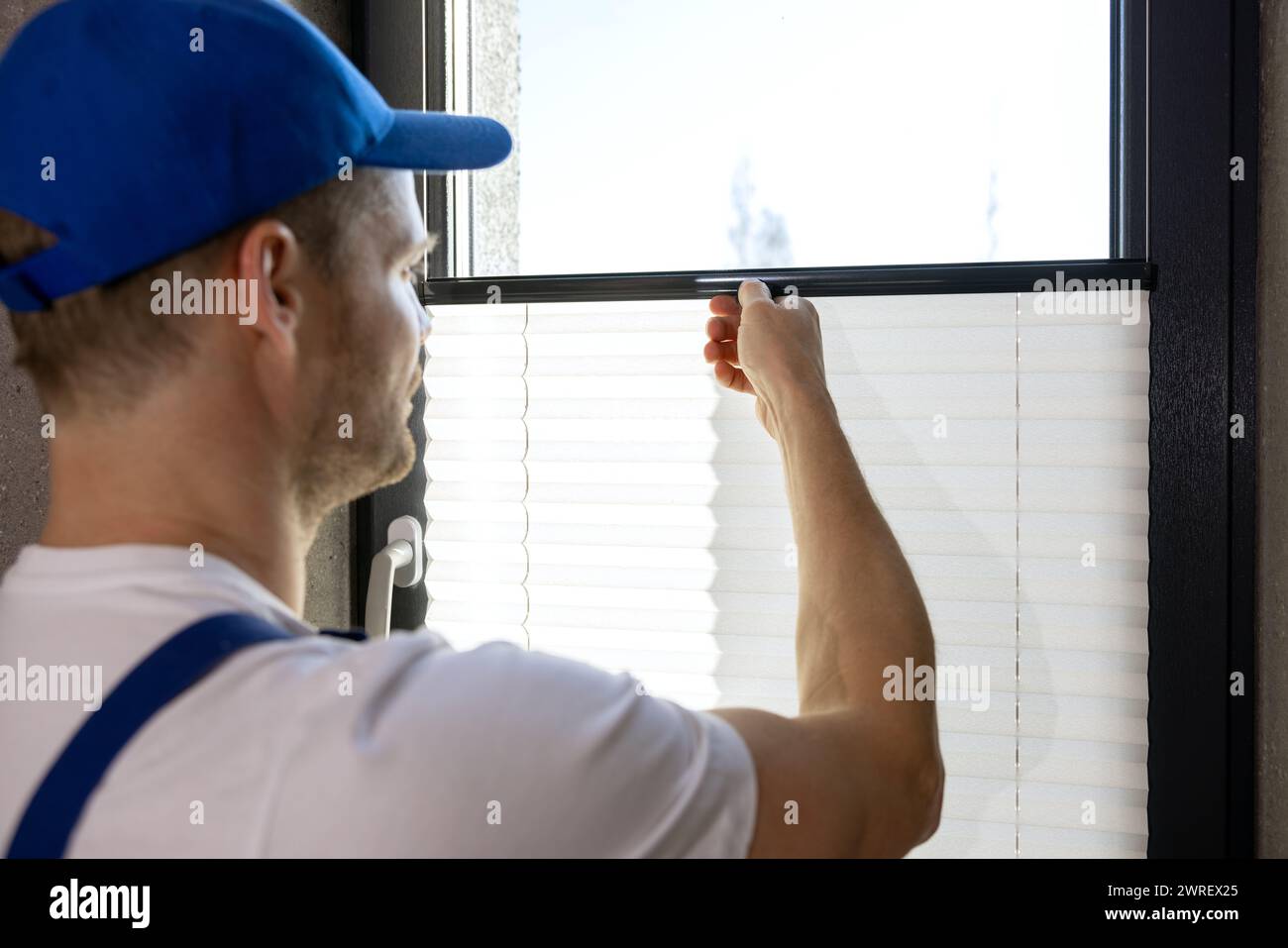 worker installing pleated blinds on the window Stock Photo - Alamy