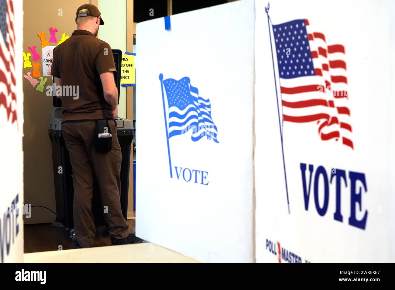 A voter drops off his paper ballot into an electronic ballot box at ...